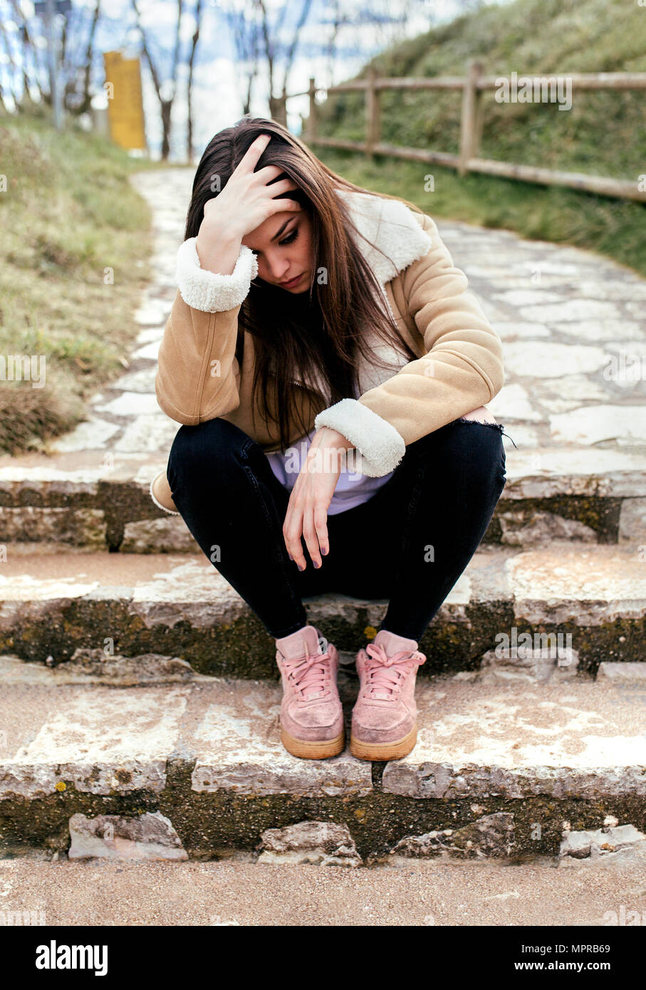 Sad young woman sitting outdoors on steps Stock Photo - Alamy