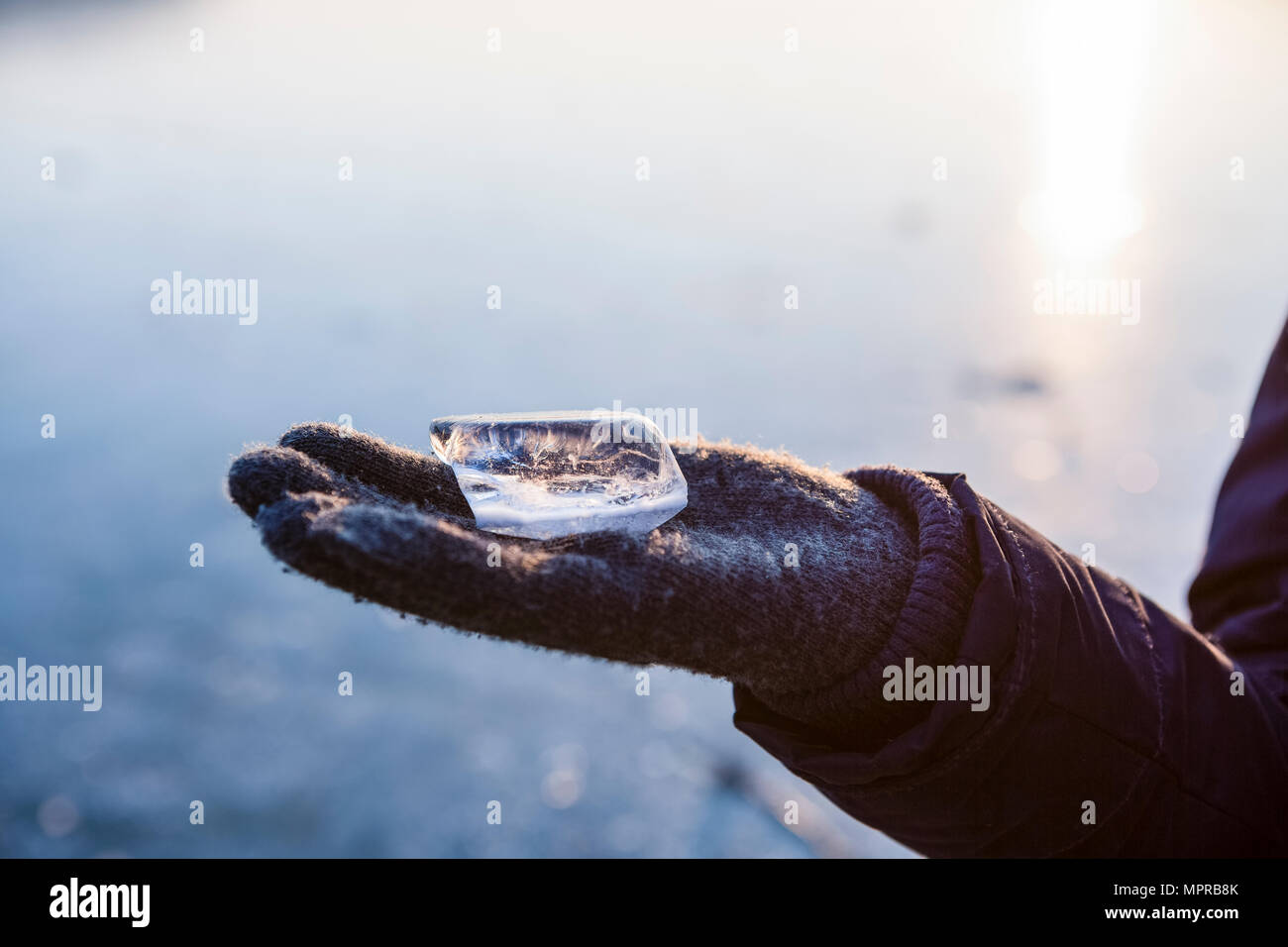 Hand with piece of ice Stock Photo - Alamy