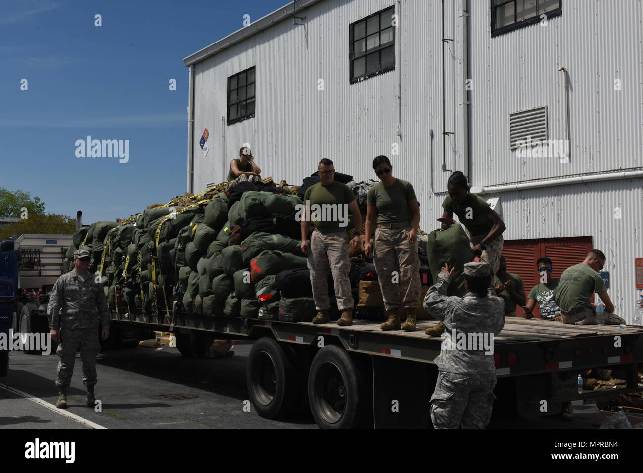 U.S. Marines load up a flat bed truck with gear to load aboard a Boeing ...
