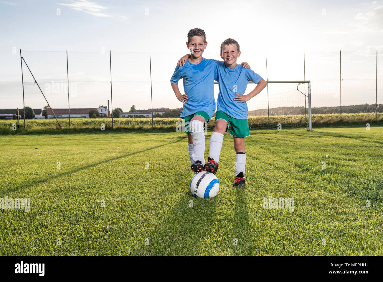 Smiling young football players embracing on football ground Stock Photo ...