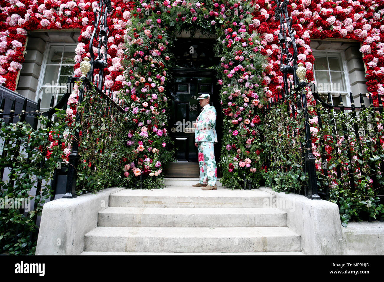 A doorman dressed in a floral patterned suit stands before the entrance ...