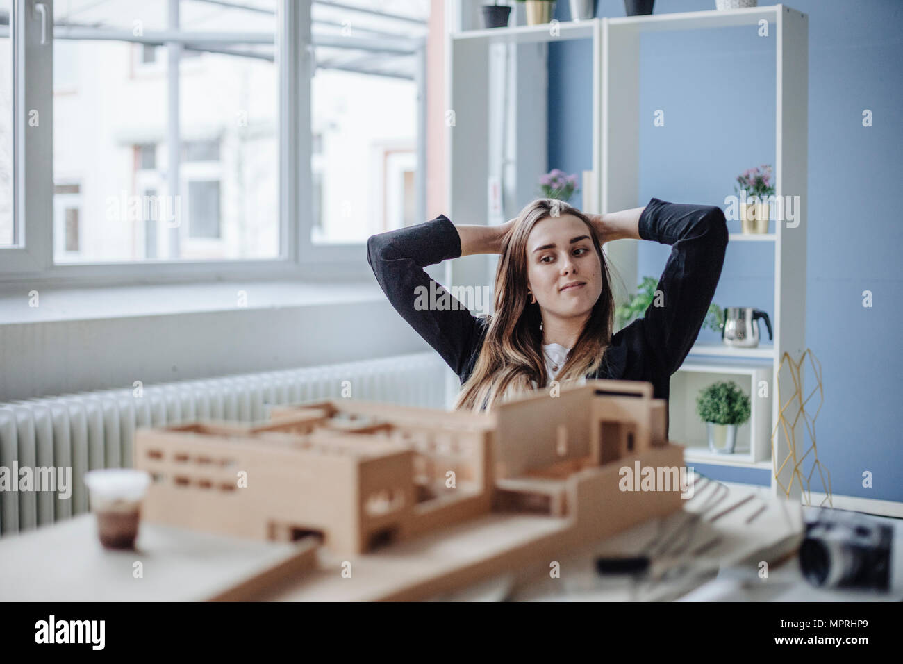 Portrait of young architect looking at architectural model in office ...