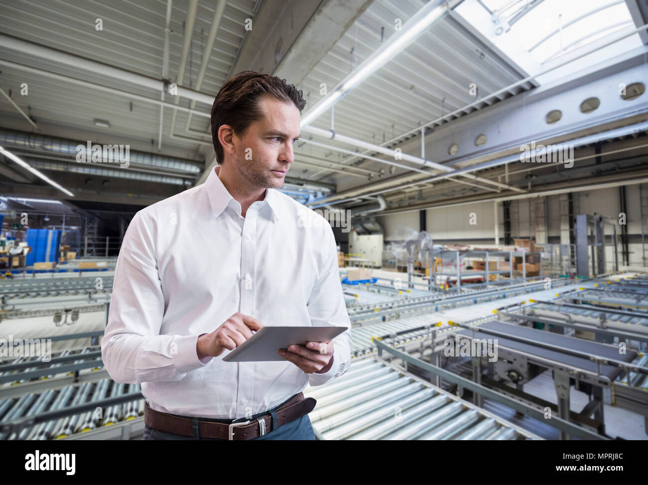 Businessman using tablet on factory shop floor Stock Photo - Alamy