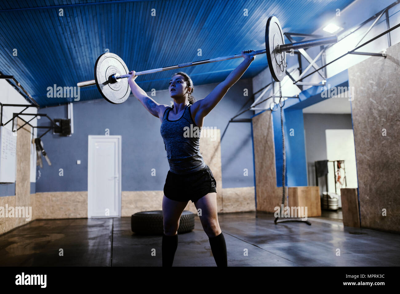 Woman lifting barbell in gym Stock Photo - Alamy