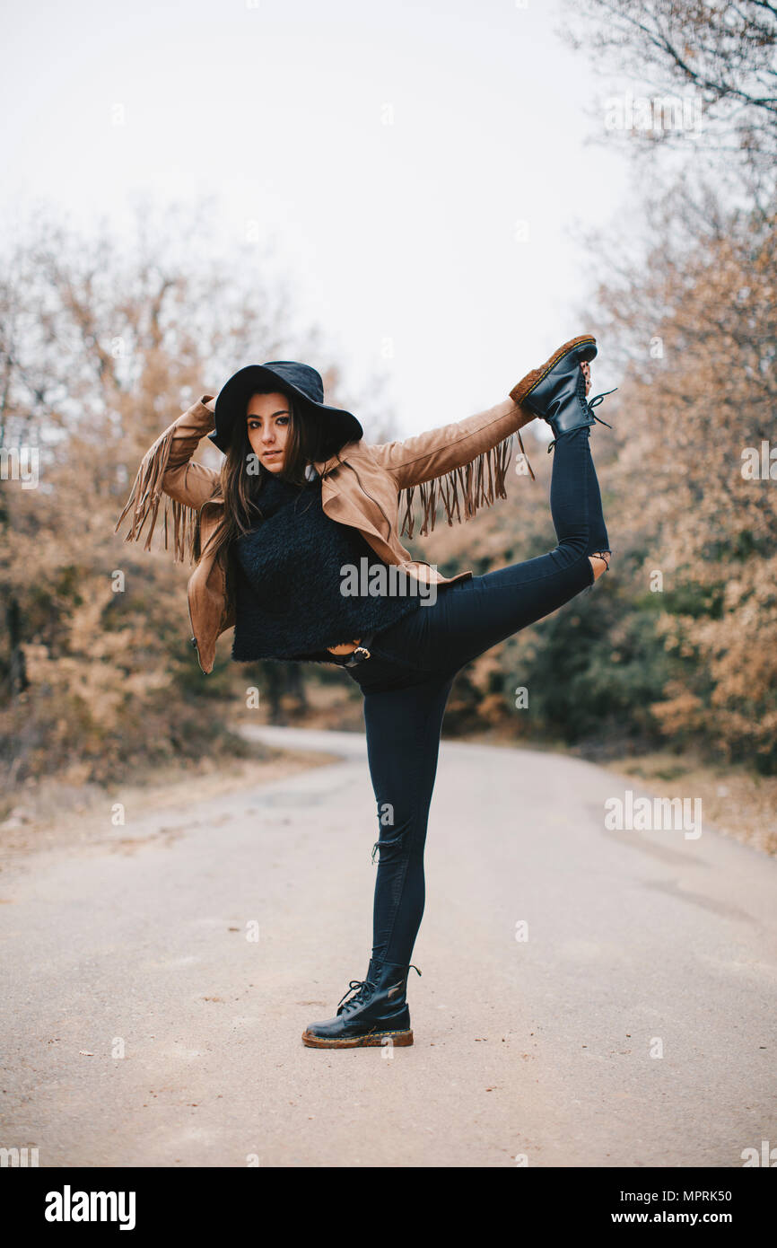 Portrait of young woman standing on one leg outdoors Stock Photo - Alamy