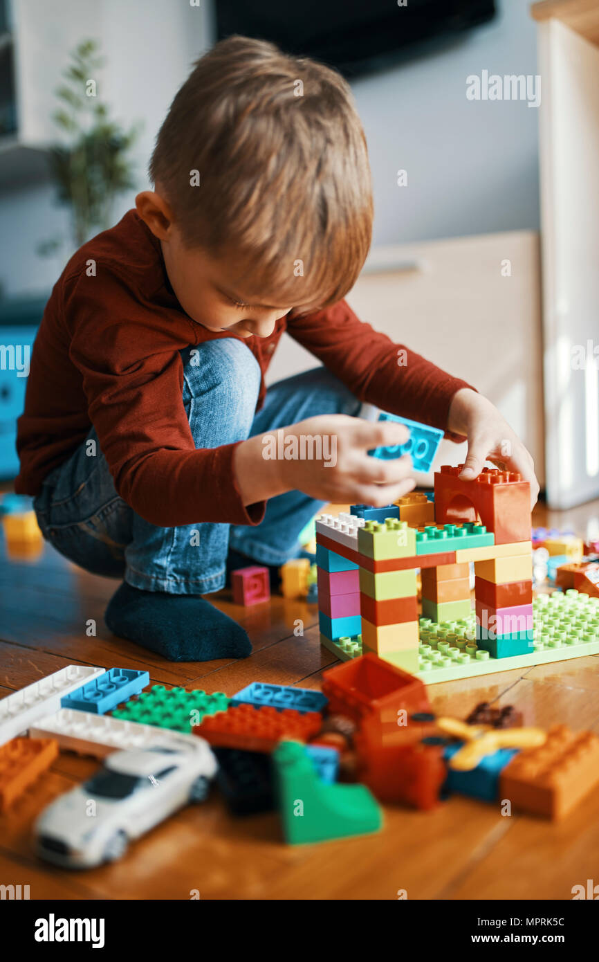Little boy playing with building bricks on the floor at home Stock ...