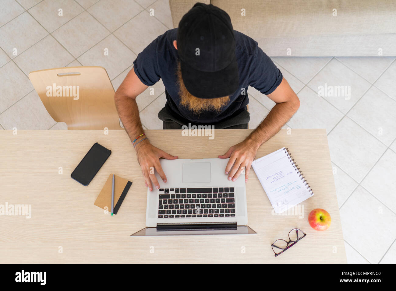 Young man wearing baseball cap sitting desk laptop hi-res stock ...