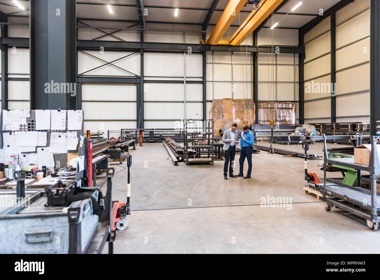 Two businessmen sharing tablet on factory shop floor Stock Photo - Alamy