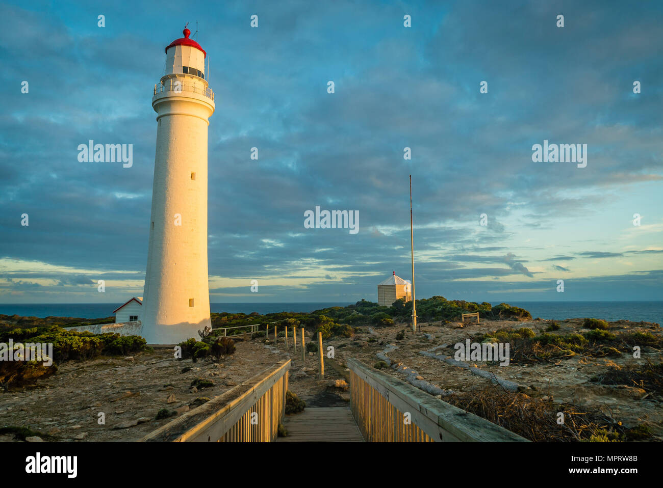 Sunset light on a red and white lighthouse at Cape Nelson state park ...