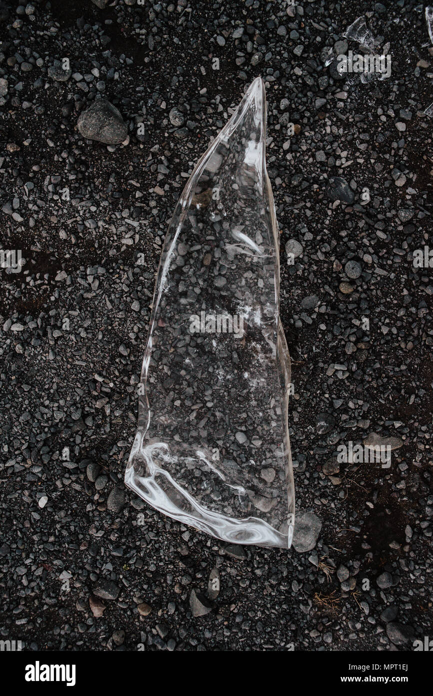 A completely clear ice crystal in triangle shape on a volcanic floor in ...
