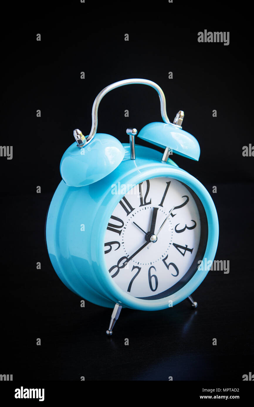 Blue alarm clock on black background Stock Photo - Alamy