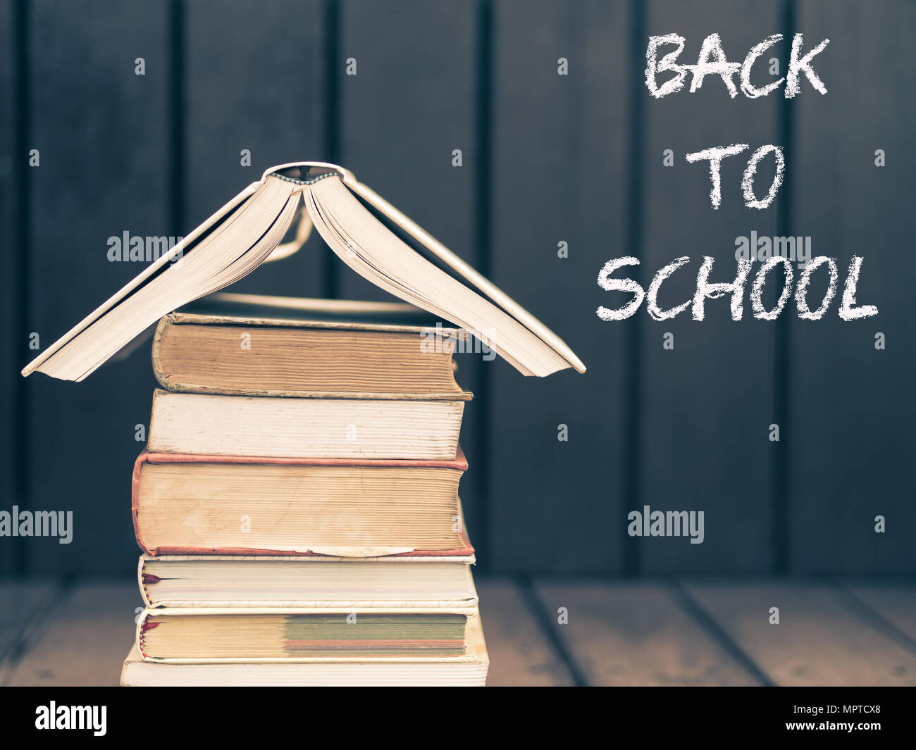 Retro style of book stacking. Open book, hardback books on brown wooden ...