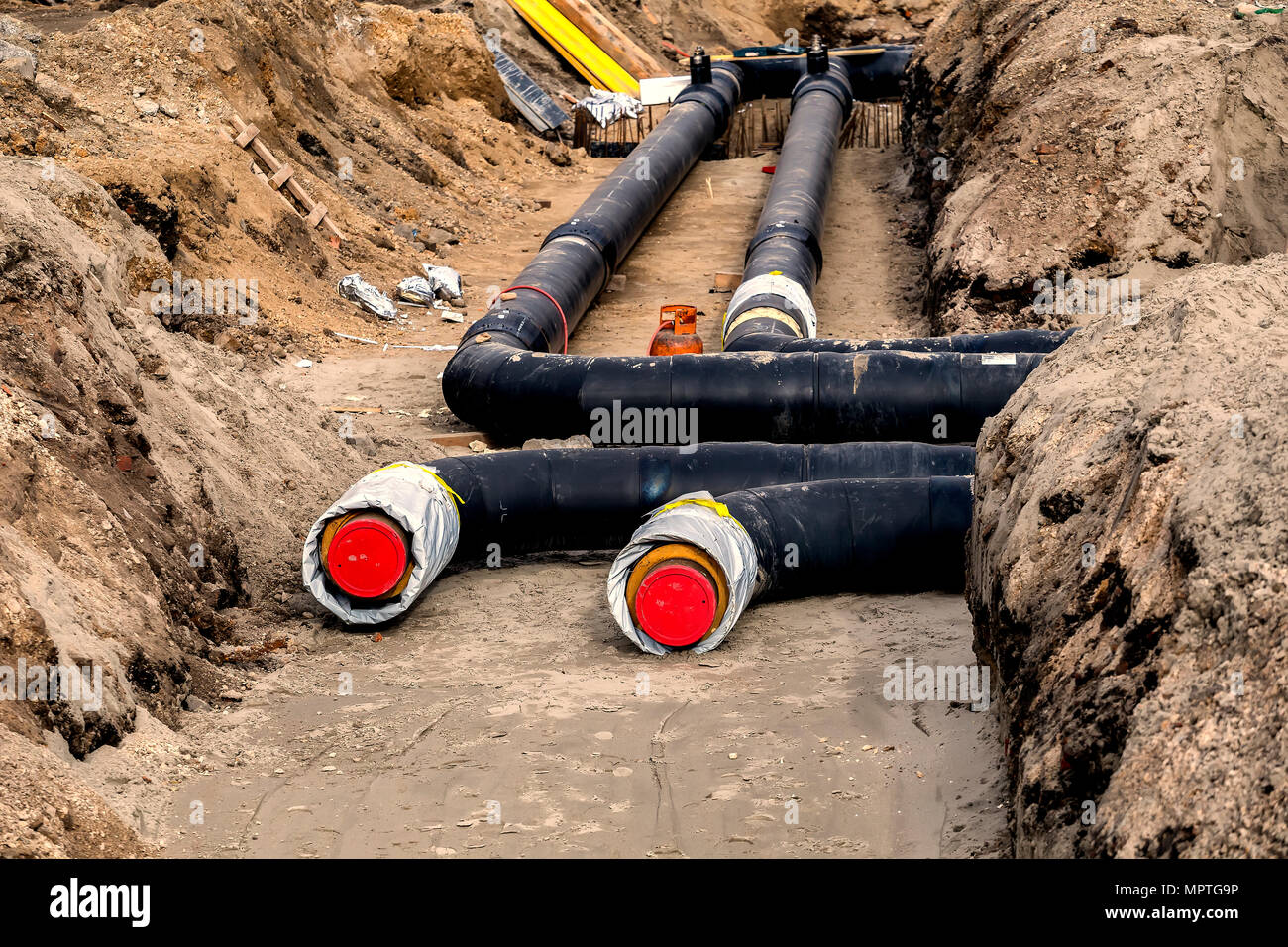 Installing district heating pipes in a trench, laying insulated pipe ...