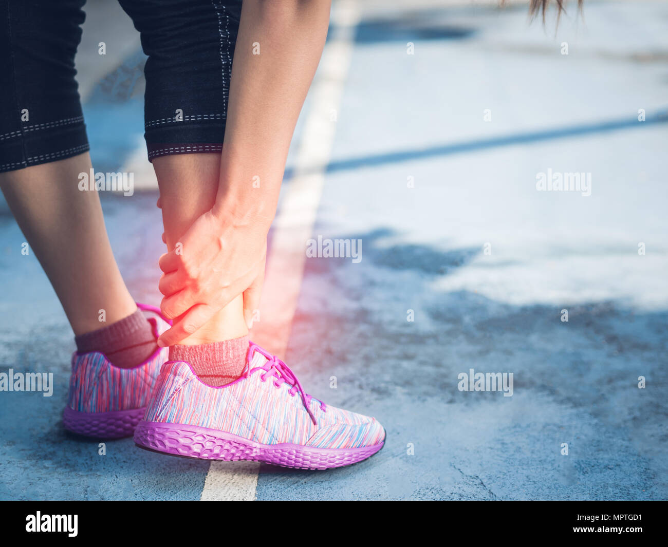 Young woman suffering from an ankle injury while exercising and running ...