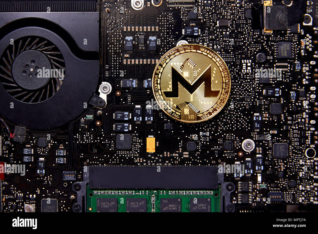 A Monero physical coin sitting on a computer motherboard with a fan and ...