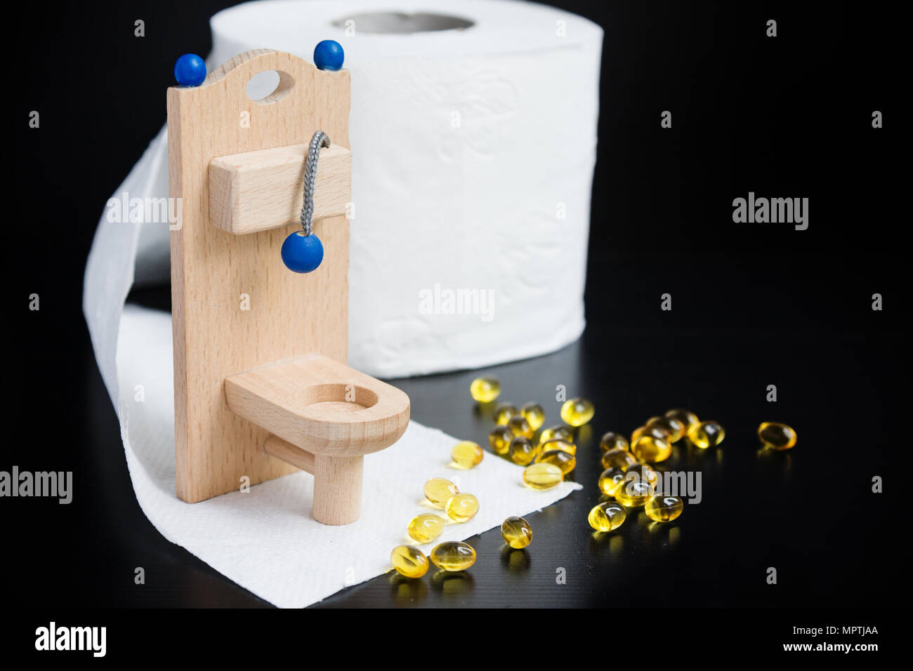 Wooden toy toilet, capsules and paper on black Stock Photo - Alamy