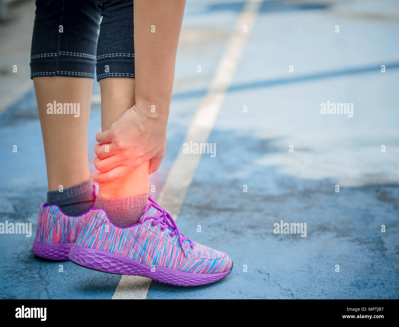 Young woman suffering from an ankle injury while exercising and running ...