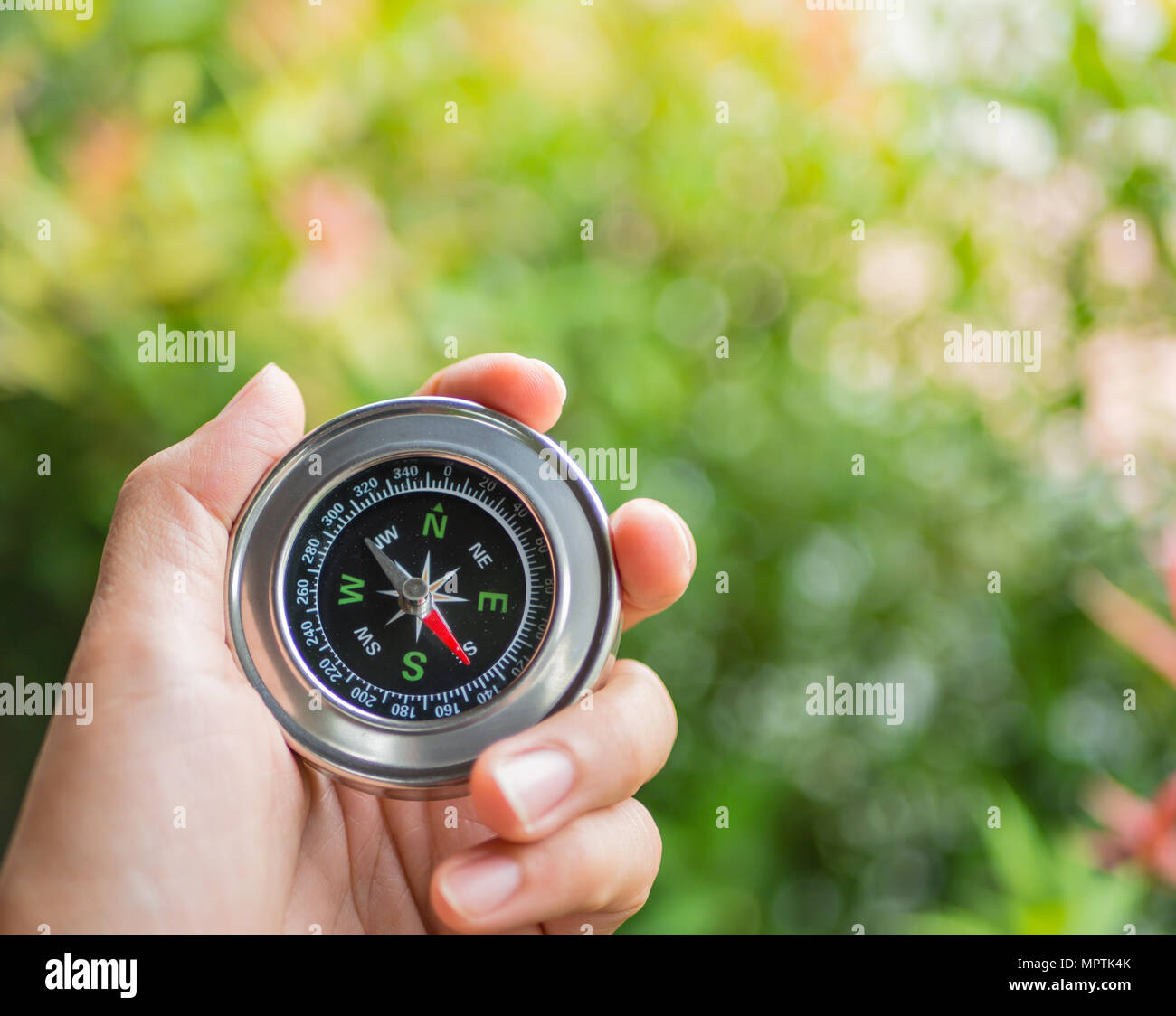 Closeup hand holding compass with tree leaves bokeh background Stock ...