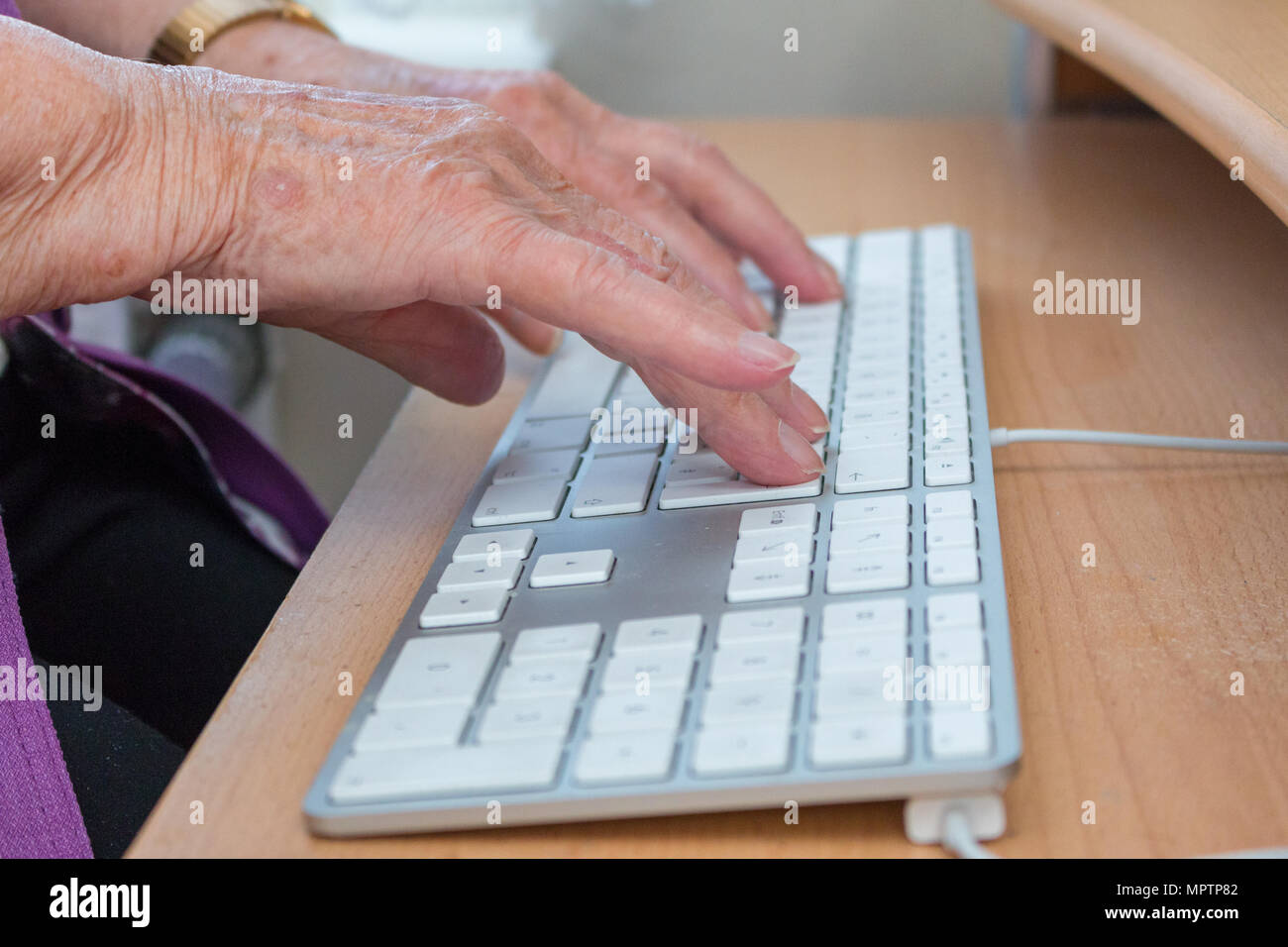 Close-up of a 95-year-old woman's old hands typing on a computer ...