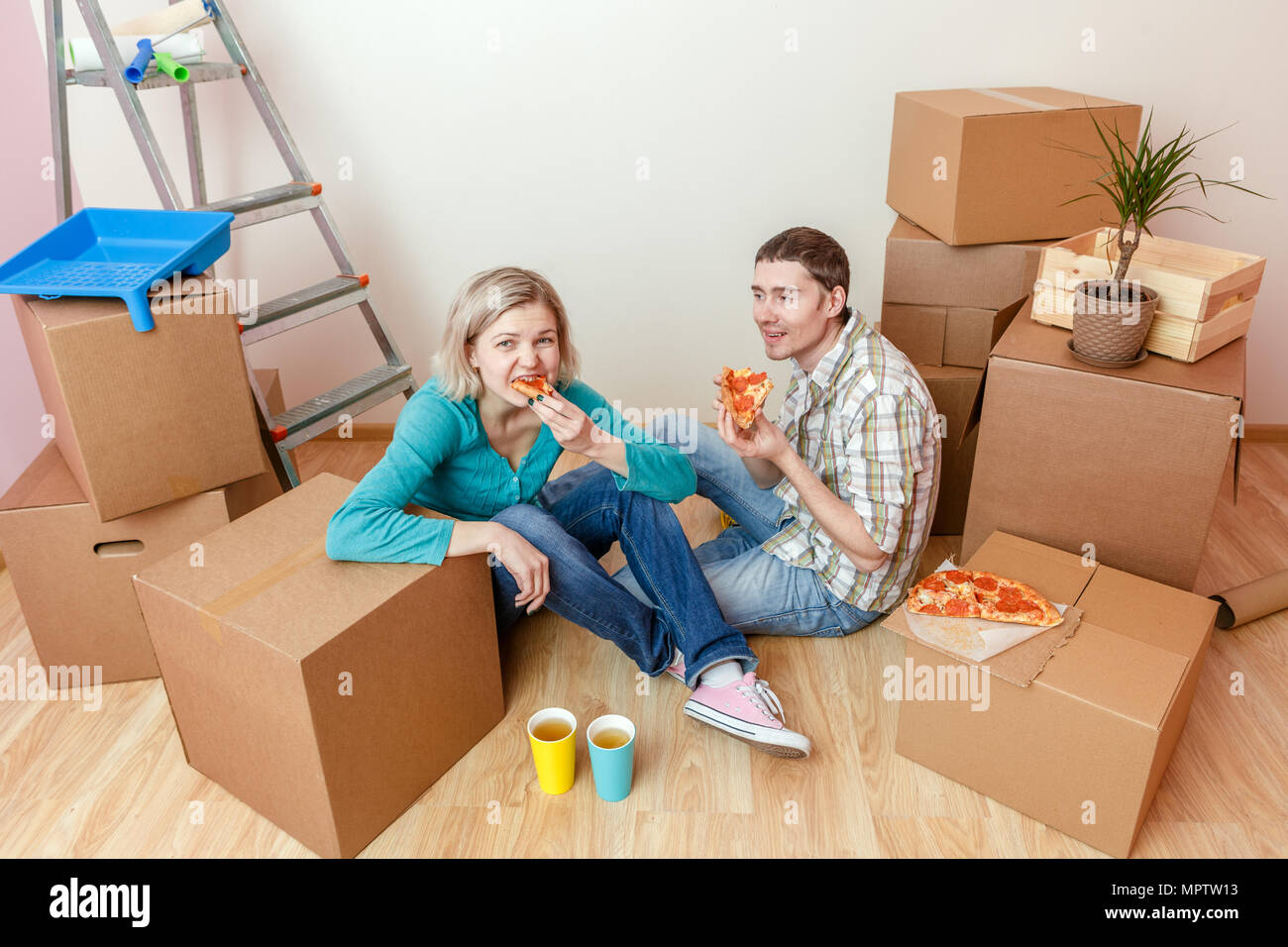 Photos of women and men eating pizza among cardboard boxes Stock Photo ...