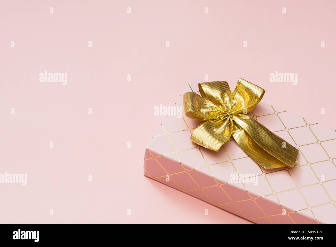 Female gift box with golden ribbon on punchy pastel pink. Birthday ...