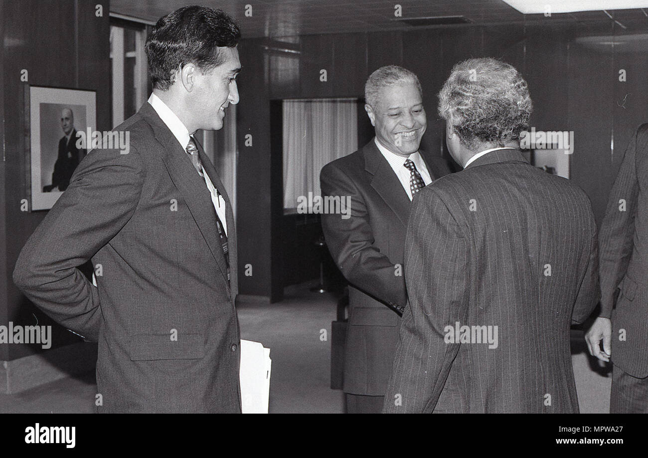 TWO MEN GREETING EACH OTHER WITH OTHER MEN WATCHING Stock Photo - Alamy
