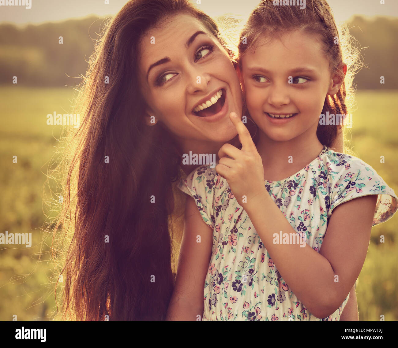 Happy excited thinking mother hugging her playful pensive kid girl and ...