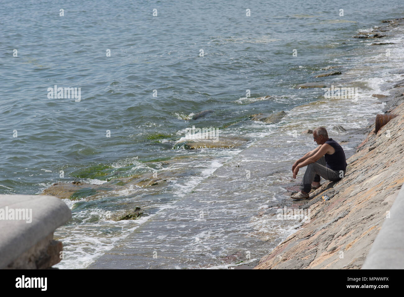 Sad man sitting by the sea Stock Photo - Alamy
