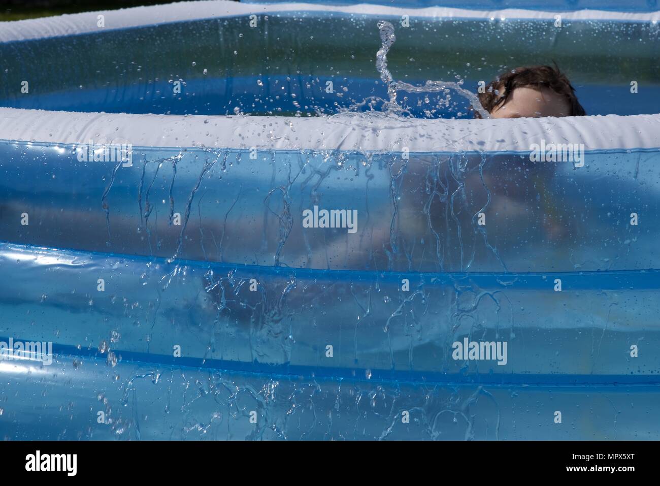 Inflatable paddling pool: a unidentifiable boy playing with a garden ...