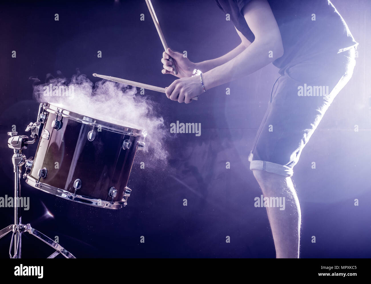 man plays musical percussion instrument with sticks closeup on a black ...
