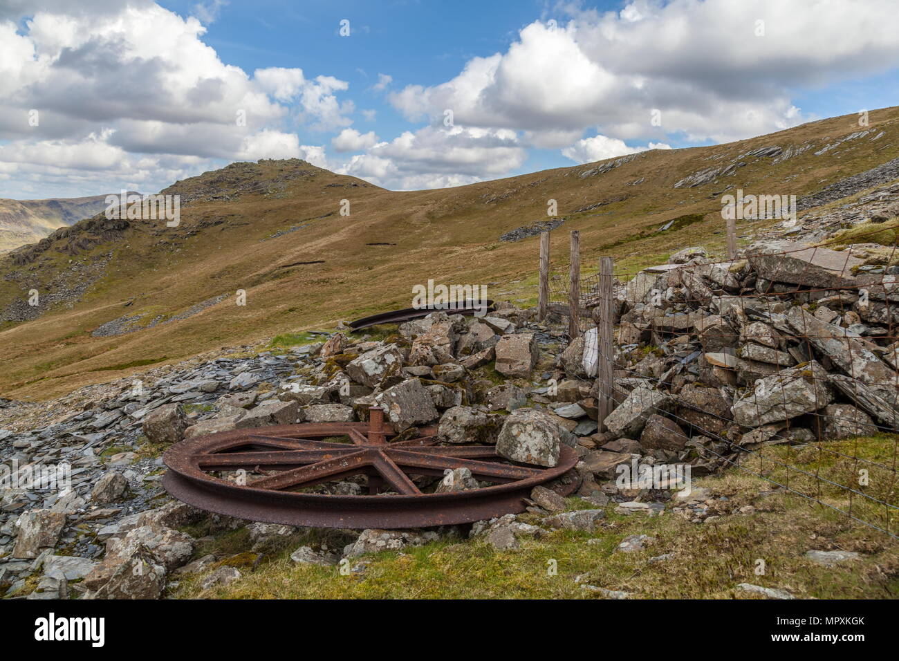 A pair of disused pit head wheels lie on the ground next to an old ...