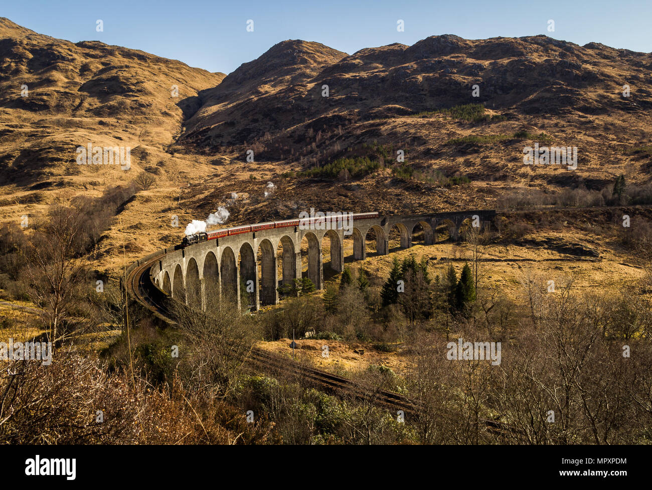 The Jacobite Steam Train crossing the Glenfinnan Viaduct on a bright ...
