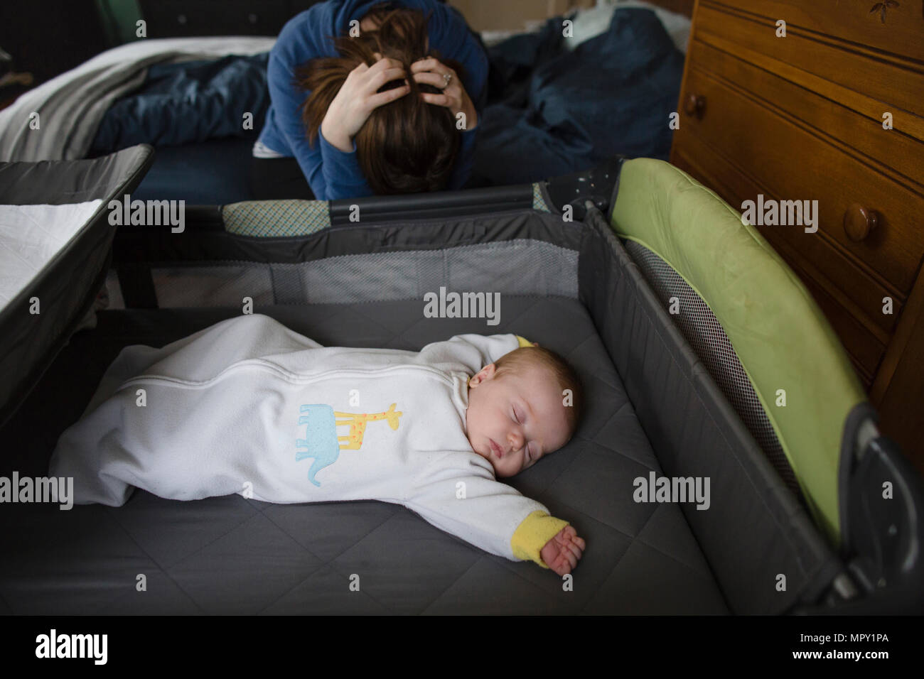 Cute baby girl sleeping in crib by depressed mother on bed at home Stock Photo - Alamy