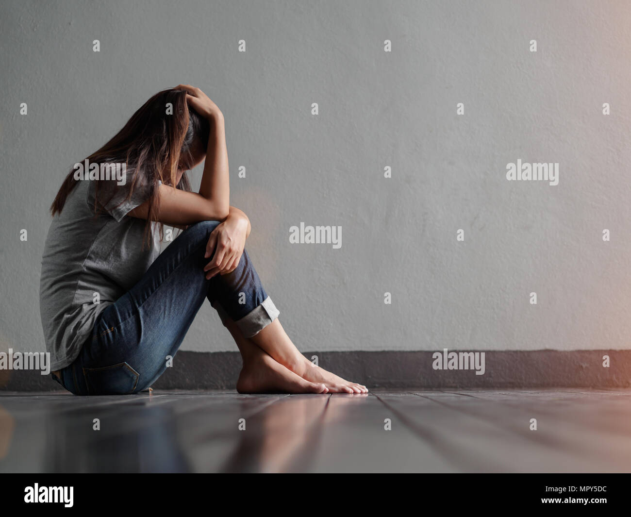 Sad woman hug her knee and cry while sitting alone in a empty room ...