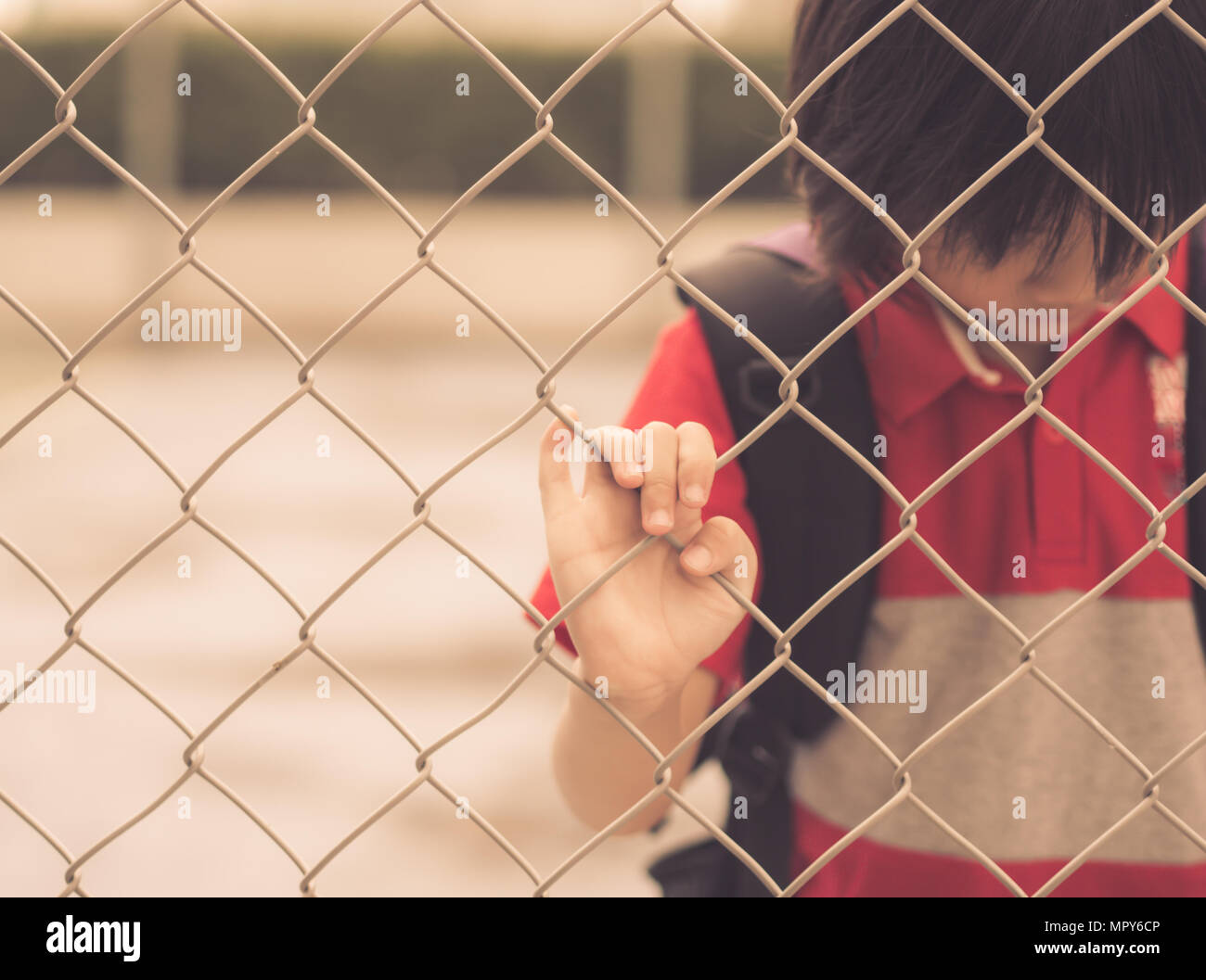 Vintage style of sad boy behind fence mesh netting. Emotions concept ...