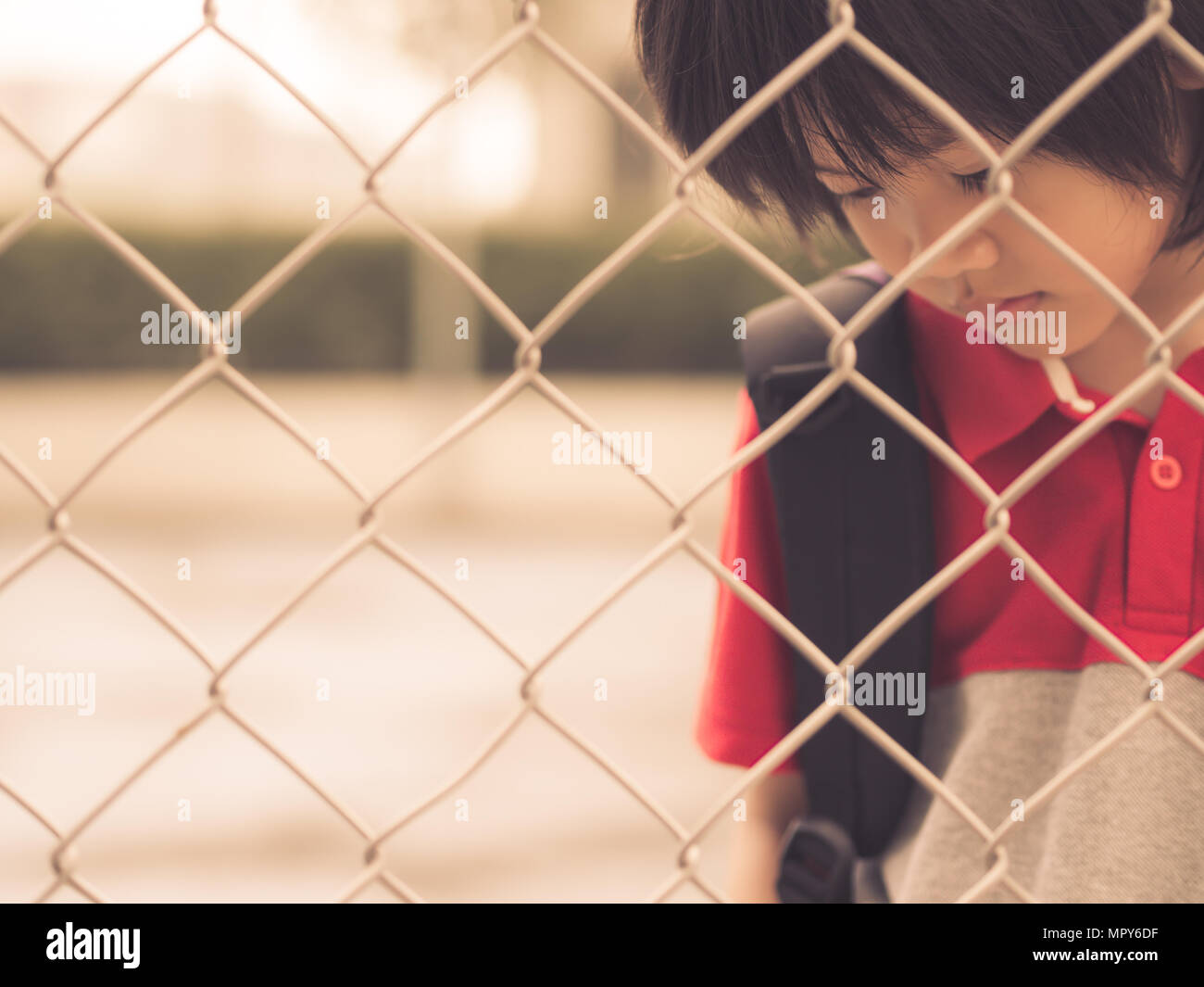 Vintage style of sad boy behind fence mesh netting. Emotions concept ...