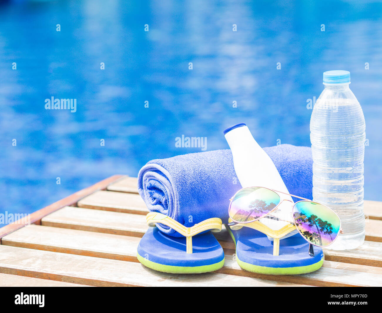 flip flops, sunglasses, blue towel and sunscreen at the side of ...
