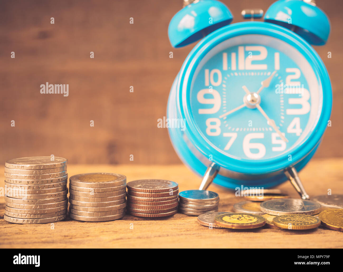 Retro stack of coins and alarm clock on wooden background. Business ...
