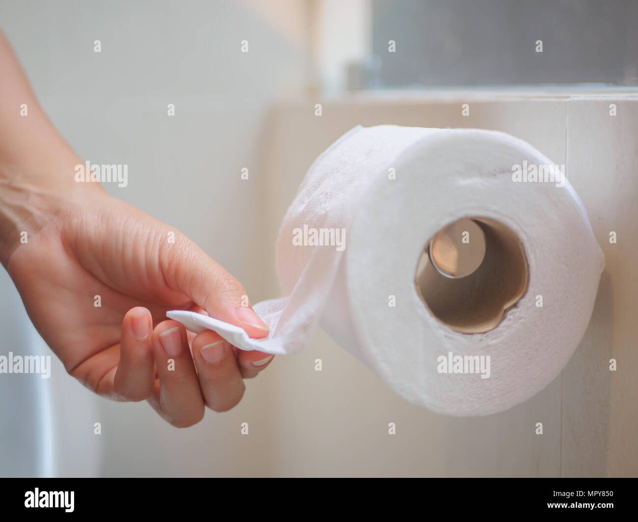 Closeup female hand picking a white tissue from tissue roll in the ...