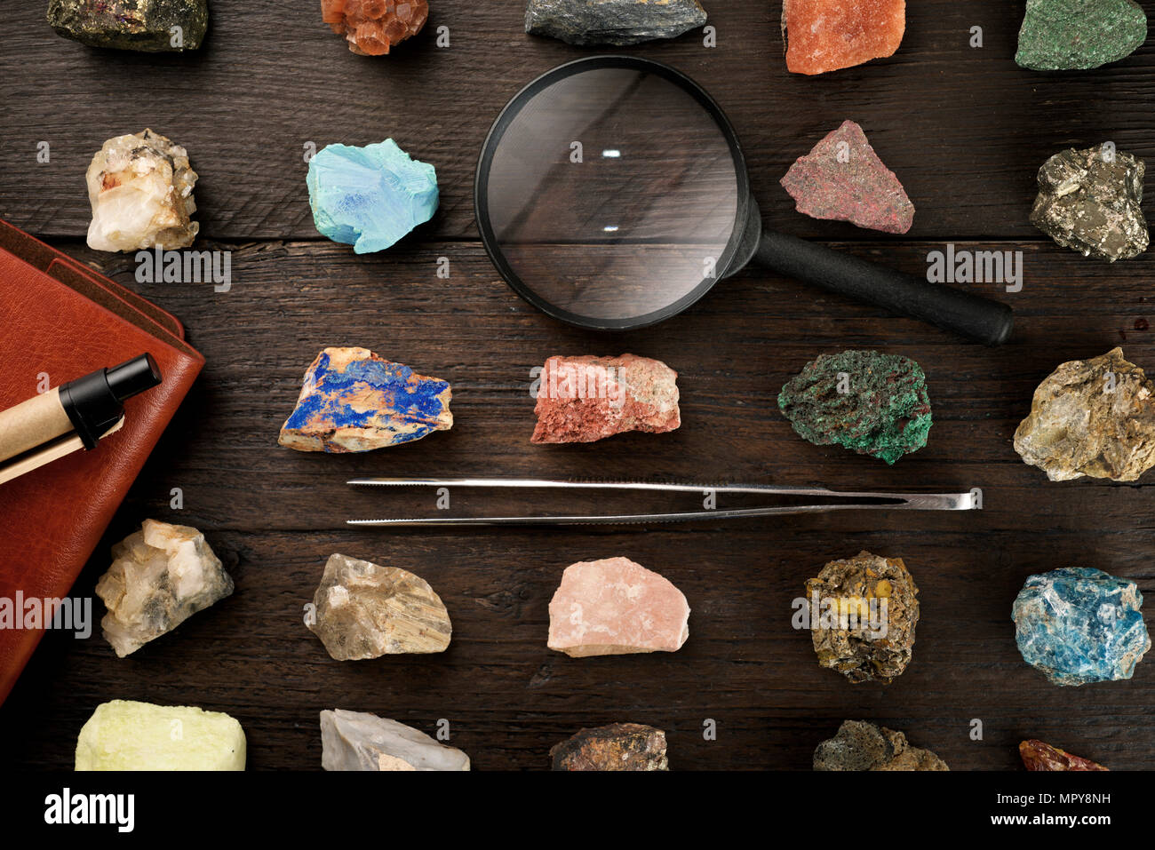 Overhead view of colorful gemstones with magnifying glass and tweezers ...
