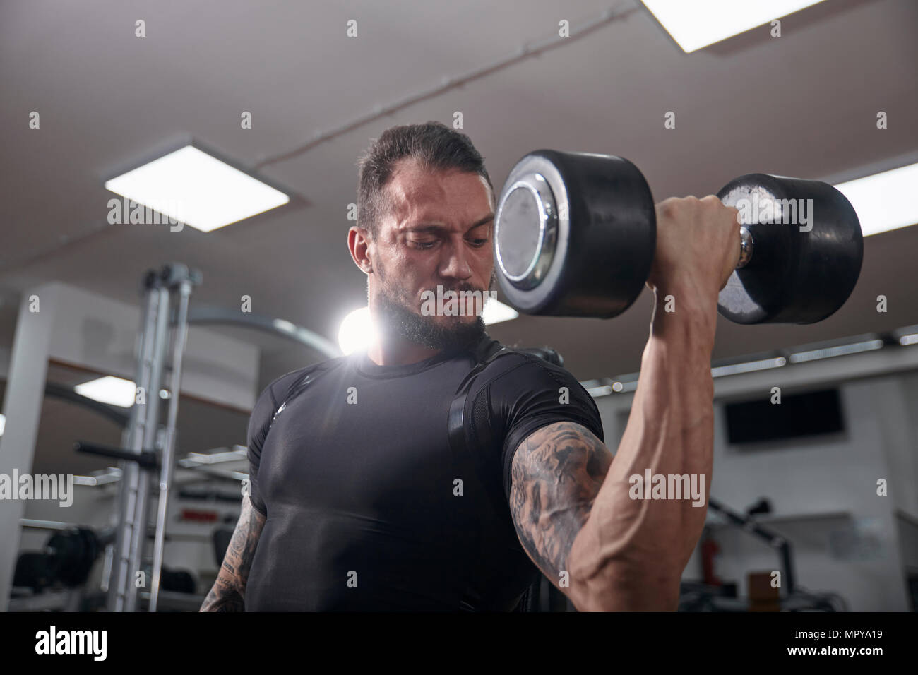 Confident muscular man lifting dumbbell at gym Stock Photo - Alamy