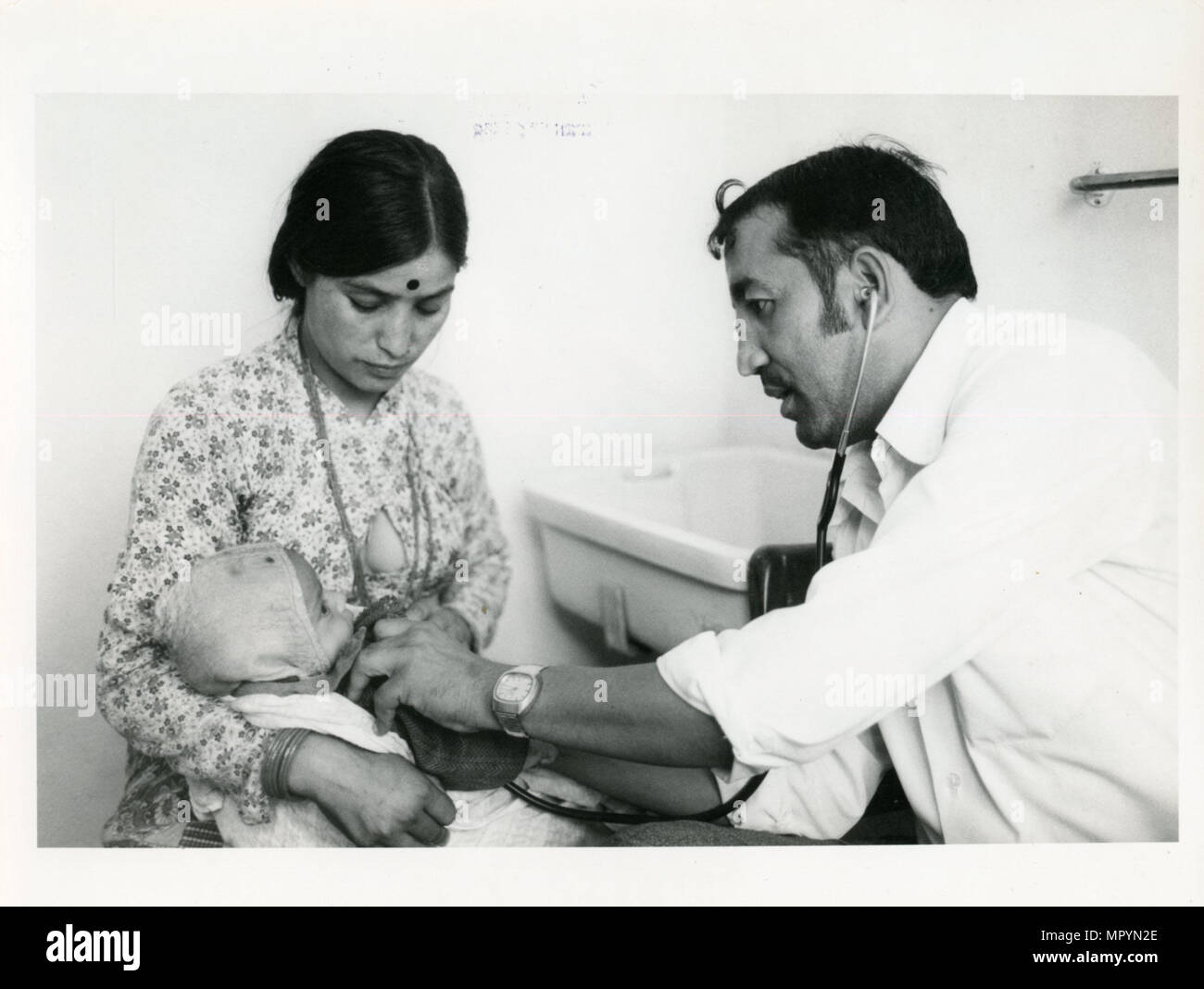doctor taking a look at baby while mother holds the baby Stock Photo ...