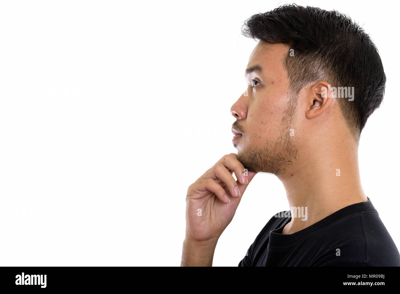 Profile view of young Asian man thinking while looking up Stock Photo ...