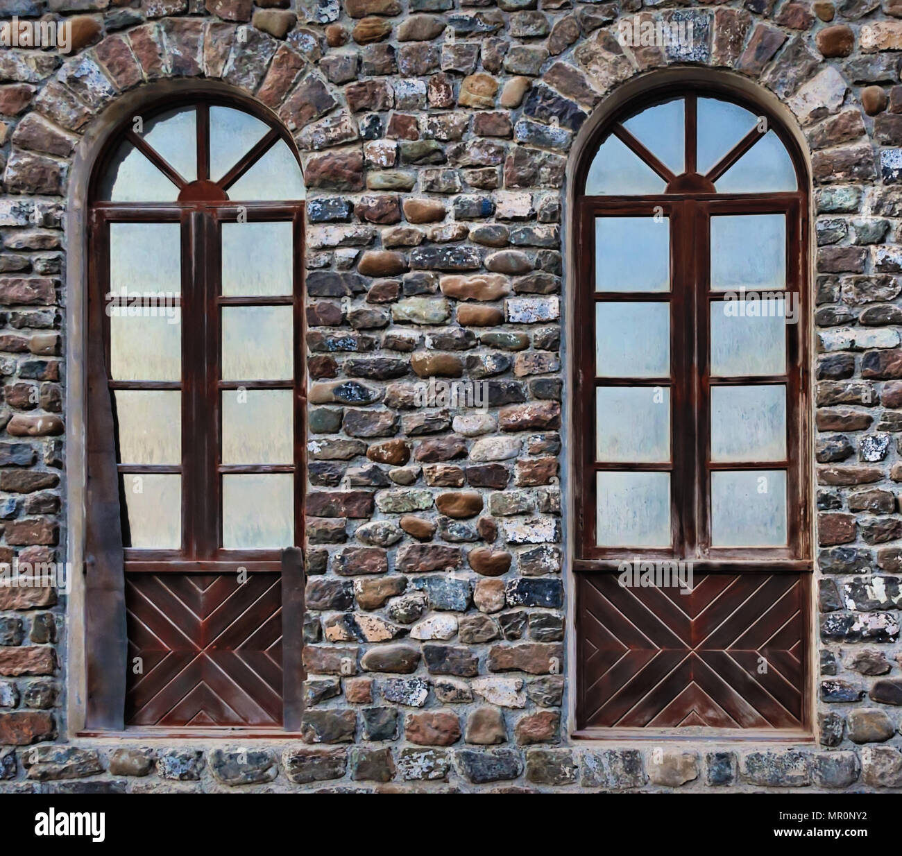 Old, traditional twin windows surrounded by stone wall from a tattered ...