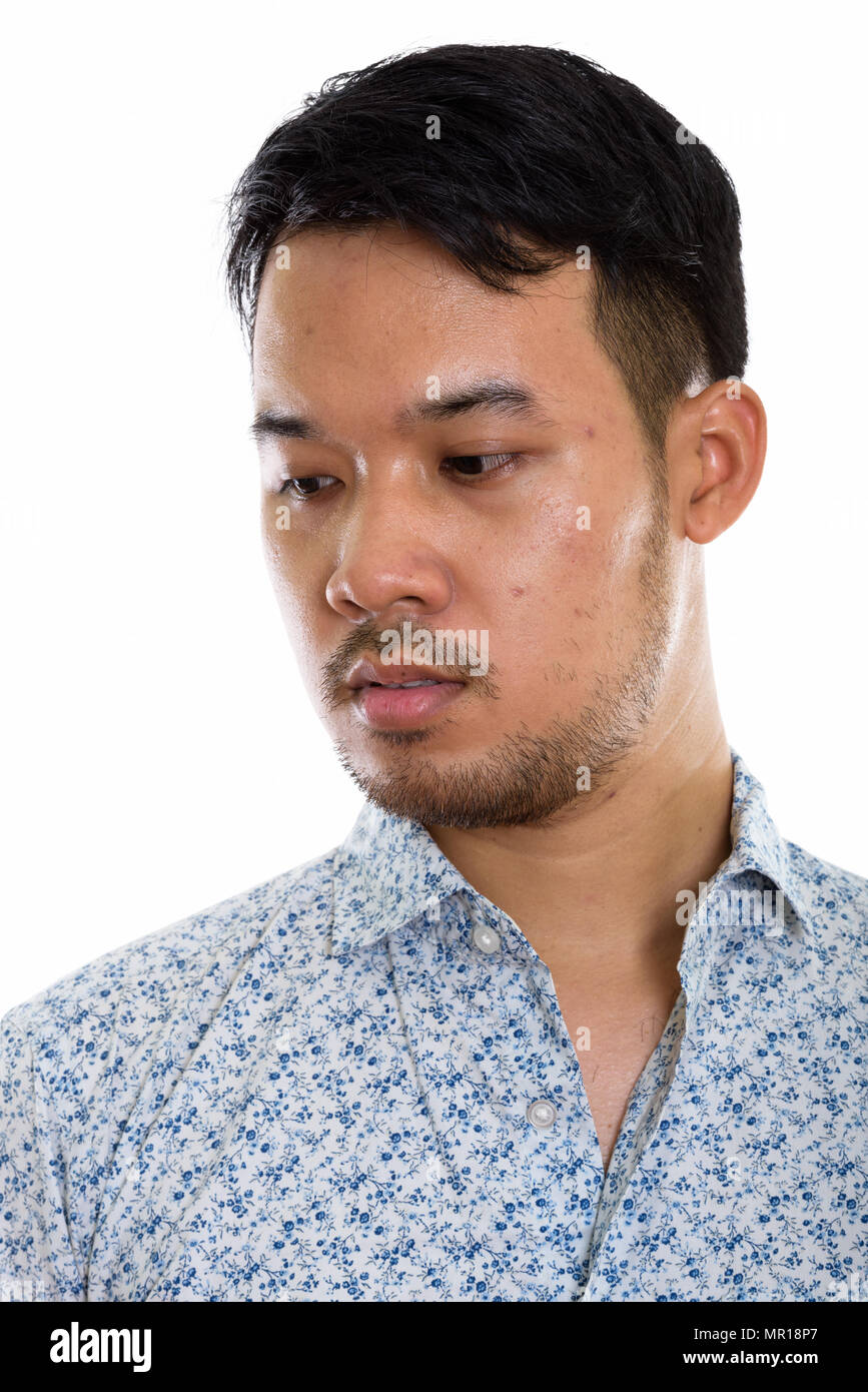 Face of young Asian man thinking while looking down Stock Photo - Alamy