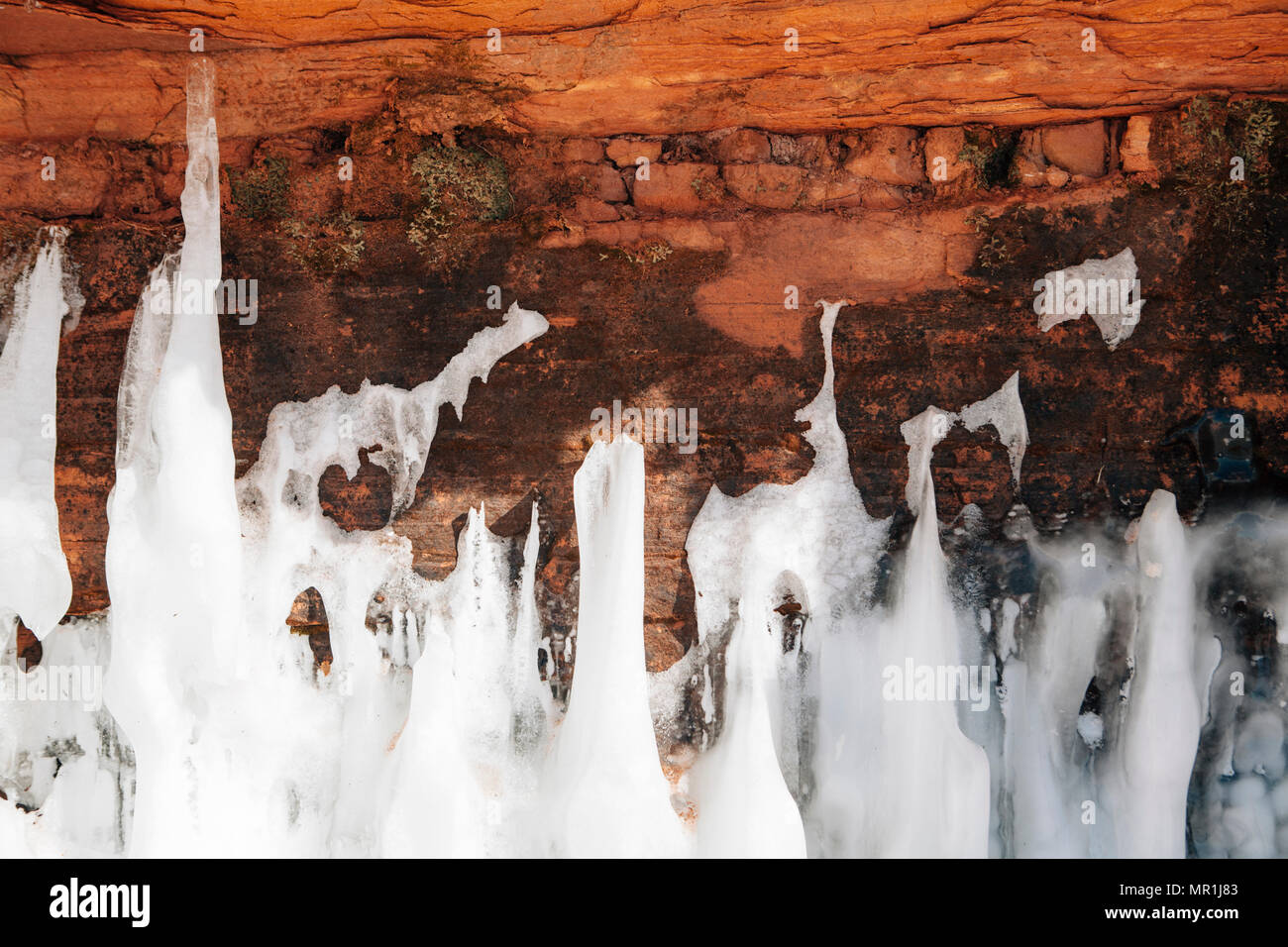 Red rocks are ice covered along the shoreline of the Apostle Islands ...