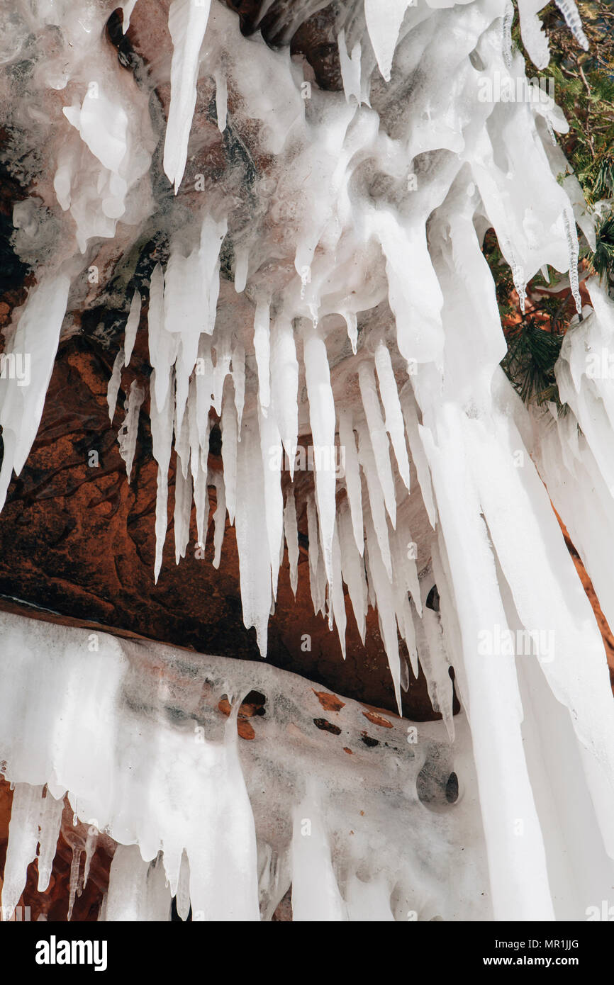 Red rocks are ice covered along the shoreline of the Apostle Islands ...
