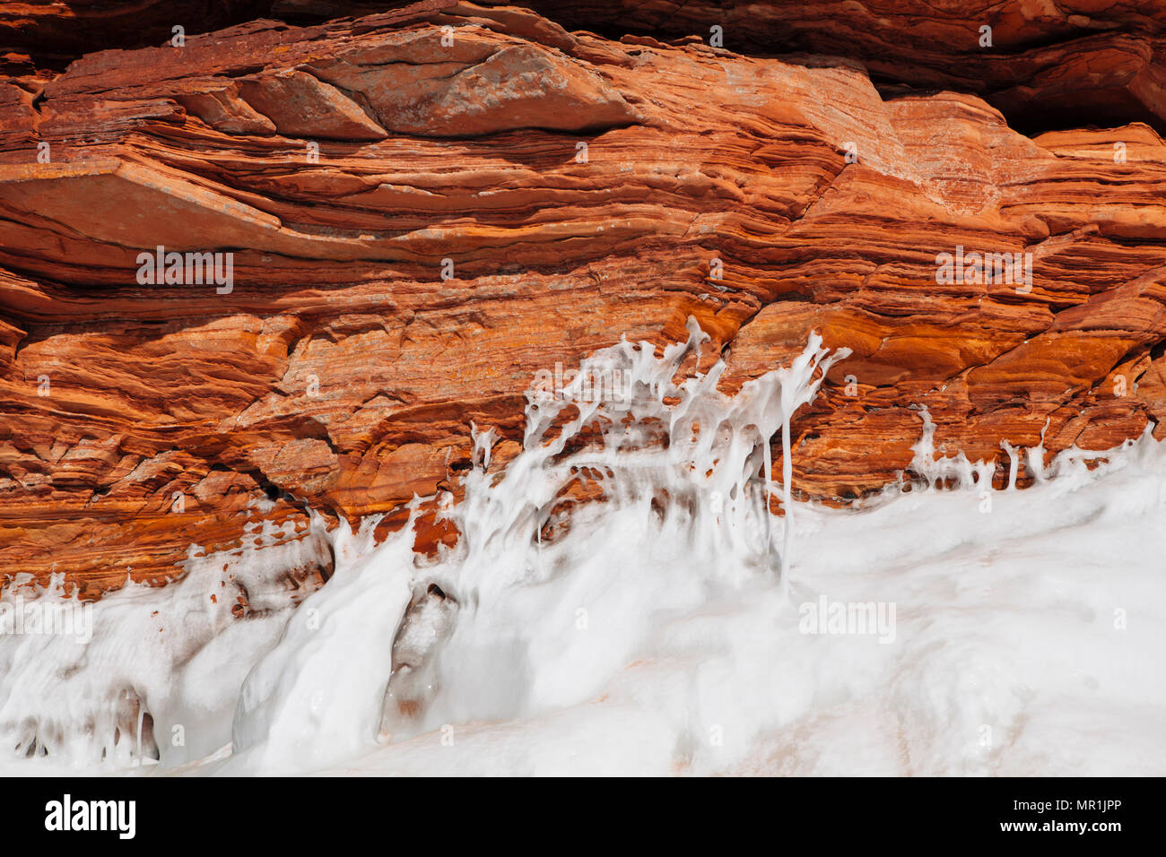 Red rocks are ice covered along the shoreline of the Apostle Islands ...