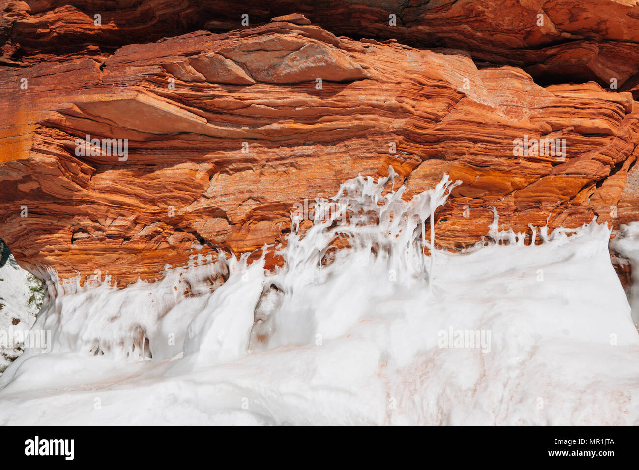 Red rocks are ice covered along the shoreline of the Apostle Islands ...