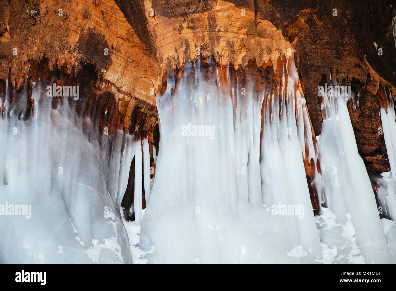 Red rocks are ice covered along the shoreline of the Apostle Islands ...
